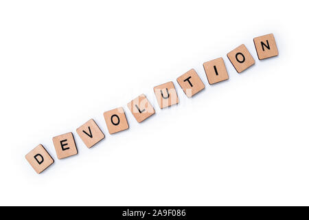 The word DEVOLUTION, spelt with wooden letter tiles over a plain white ...
