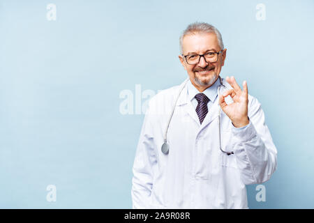 Mature doctor with stethoscope on blue background, closeup Stock Photo ...