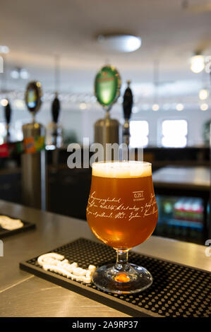 A pint of Carlsberg lager at the bar in the pub with a burning log fire ...