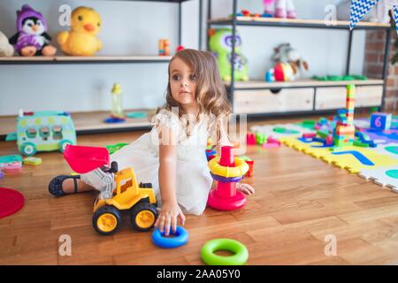 Adorable toddler building pyramid using hoops around lots of toys at ...