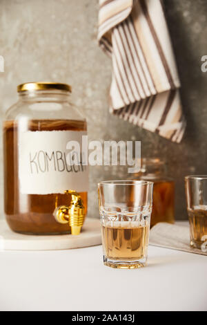 jar with kombucha near glasses on textured grey background with striped ...