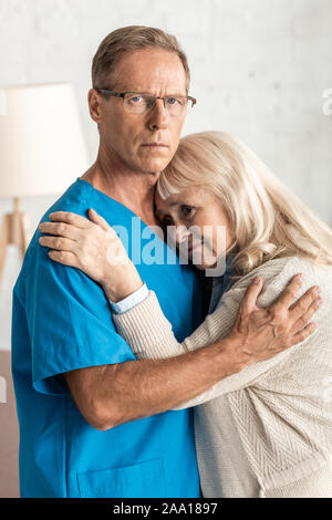 Doctor, hug and sad elderly woman in hospital for support, comfort and ...