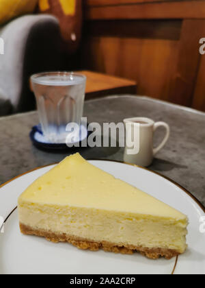 Smooth creamy cheesecake in white fluted dish with fresh mint sprig ...