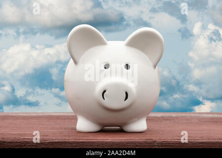 White piggy bank with cloudy sky background. Saving or investment ...