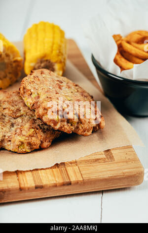 Grilled corn on the cob on round white plate over white wooden ...