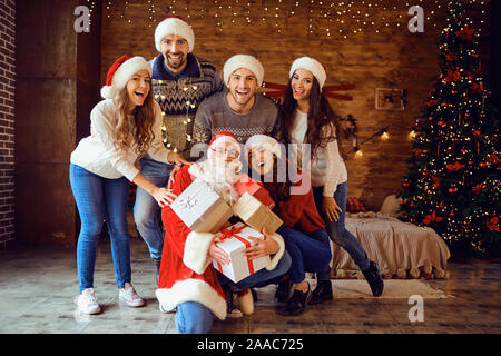 People with Christmas presents and Santa hats near green wall Stock ...