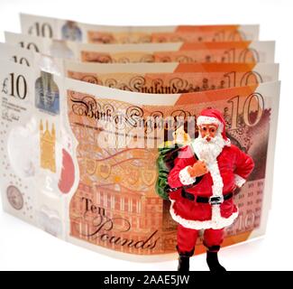 A santa claus figurine standing in front of some new ten pound notes ...