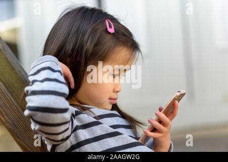 Little girl staring at cellphone screen at night. Child watching ...