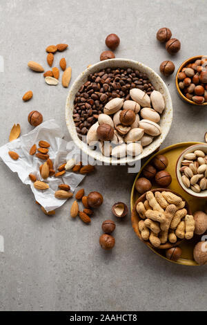 Mixed nuts in different bowls on wooden table. Top view with place for ...