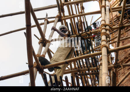 Indian construction workers balancing on scaffolding against a newly ...