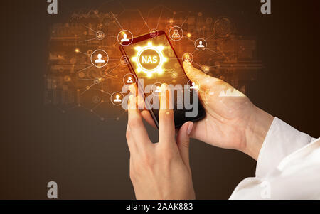 Female hand holding smartphone with NAS abbreviation, modern technology ...