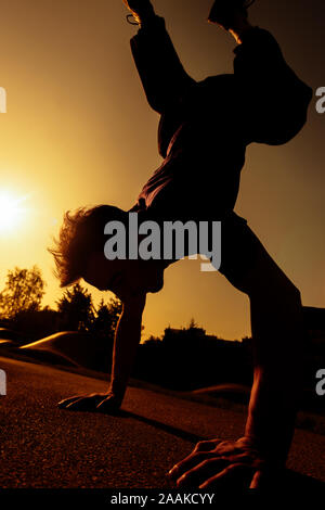 Young muscular guy performing parkour tricks outdoors at a skateboard ...