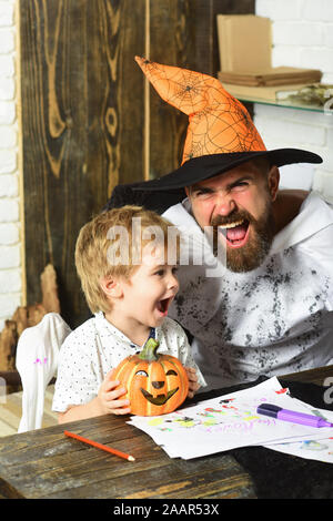 Witcher and little magician make Halloween decor. Guy and boy on wooden ...