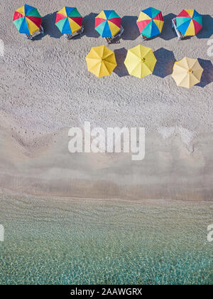 An aerial shot of a yellow beach umbrella and a person in a swimsuit ...