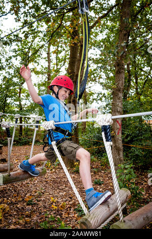 Child climbing and balancing on rope course obstacles in treetop ...