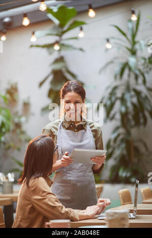 Portrait of smiling waitress using digital tablet Stock Photo - Alamy