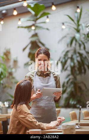 Portrait of smiling waitress using digital tablet Stock Photo - Alamy