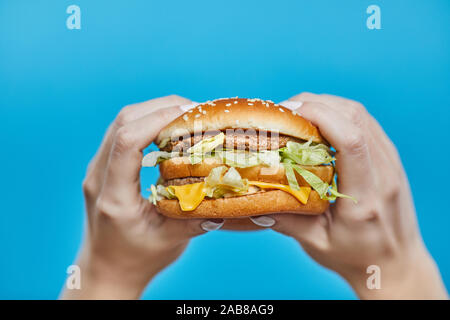 Woman eating burger on blue background Stock Photo - Alamy