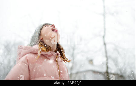 Adorable young girl catching snowflakes with her tongue in beautiful ...