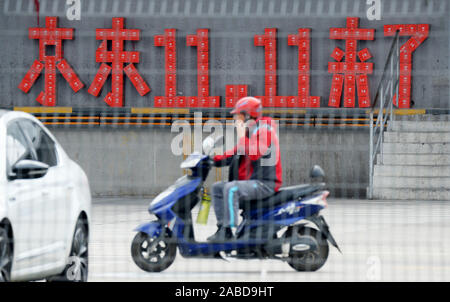 Staff pass in front of slogans related to Single's Day, also known as ...