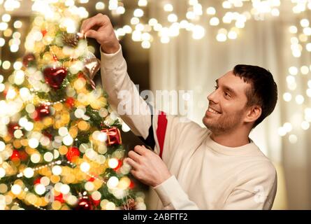 happy man decorating christmas tree at home Stock Photo - Alamy