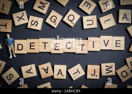Word of wooden letters - detective, on a gray background with a glass ...