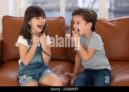 brother and sister playing a doctor with stethoscope - isolated on ...