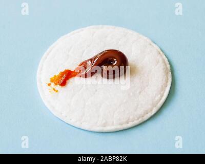 An iodine ointment on a cotton pad near an open tube over a blue ...