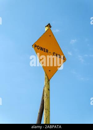 A diamond shaped yellow warning sign saying "Power Cable Warning ...