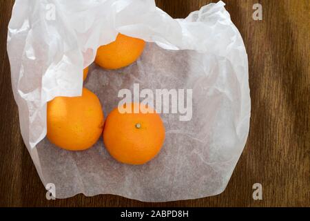 Tangerines in yellow crumpled craft paper on a dark wooden kitchen ...