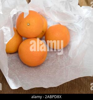 Tangerines in yellow crumpled craft paper on a dark wooden kitchen ...