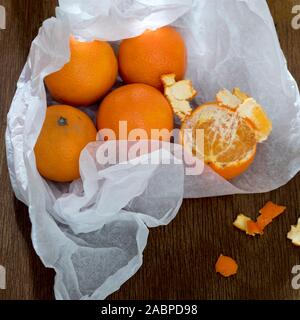 Tangerines in yellow crumpled craft paper on a dark wooden kitchen ...