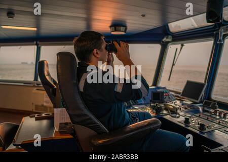 Captain on ship looking through a telescope Stock Photo - Alamy