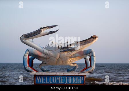 Oversized statue of a crab rising from the sea just offshore welcoming ...