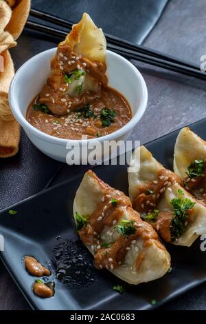 Fried Chinese Hunan pork dumplings with spicy peanut butter sauce and ...