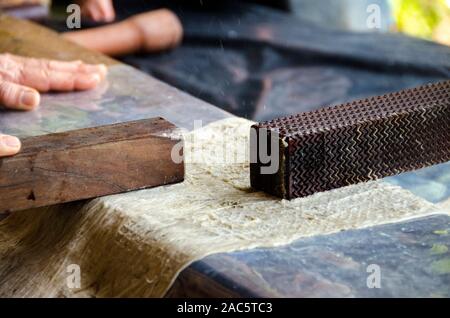 A close-up of Roen Hufford using a wooden beater to make kapa (or tapa ...