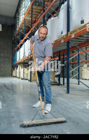 Guy sweeping the floor Stock Photo - Alamy