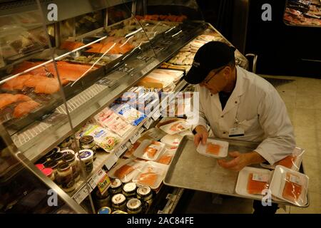 Fishmonger laying out shrink-wrapped fresh fish fillets in the fish ...