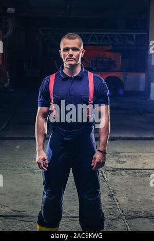 firefighter portrait wearing shirt and red throuser suspenders, holding ...