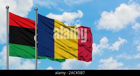 Chad and Libya flag waving in the wind against white cloudy blue sky ...