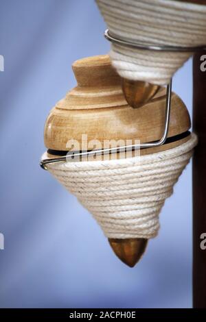a traditional wooden spinning top with a string coiled in its axis on a ...