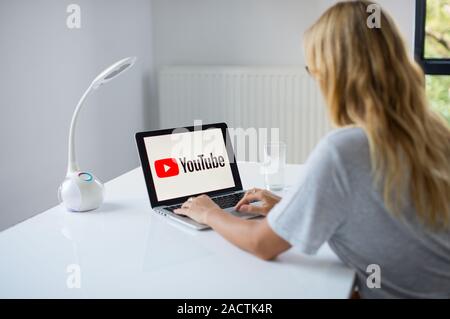 Young woman using laptop with YouTube logo in the screen seeting at the ...