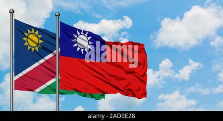 Taiwan and Namibia flag waving in the wind against white cloudy blue ...