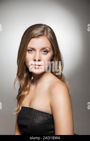 A young woman with long wavy hair stands atop a jagged rocky cliff ...