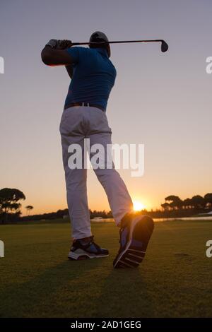 golfer hitting long shot with driver on course at beautiful sunset ...