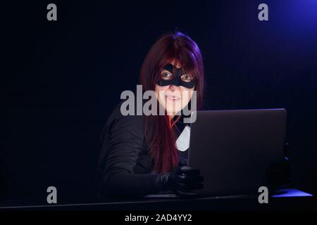 Woman spy in black mask by computer at night Stock Photo - Alamy