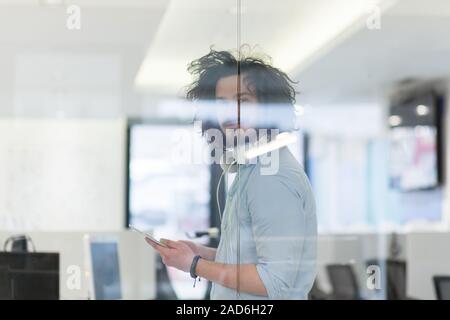 Happy businessman using tablet computer while leaning on desk in office ...
