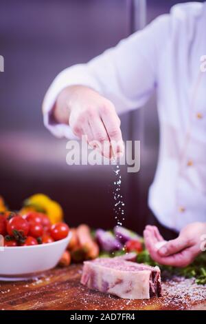 Master Chef hands putting salt on juicy slice of raw steak with ...