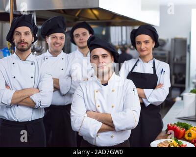 Group portrait of professional chefs posing together in modern kitchen ...