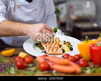 cook chef decorating garnishing prepared meal dish on the plate in ...